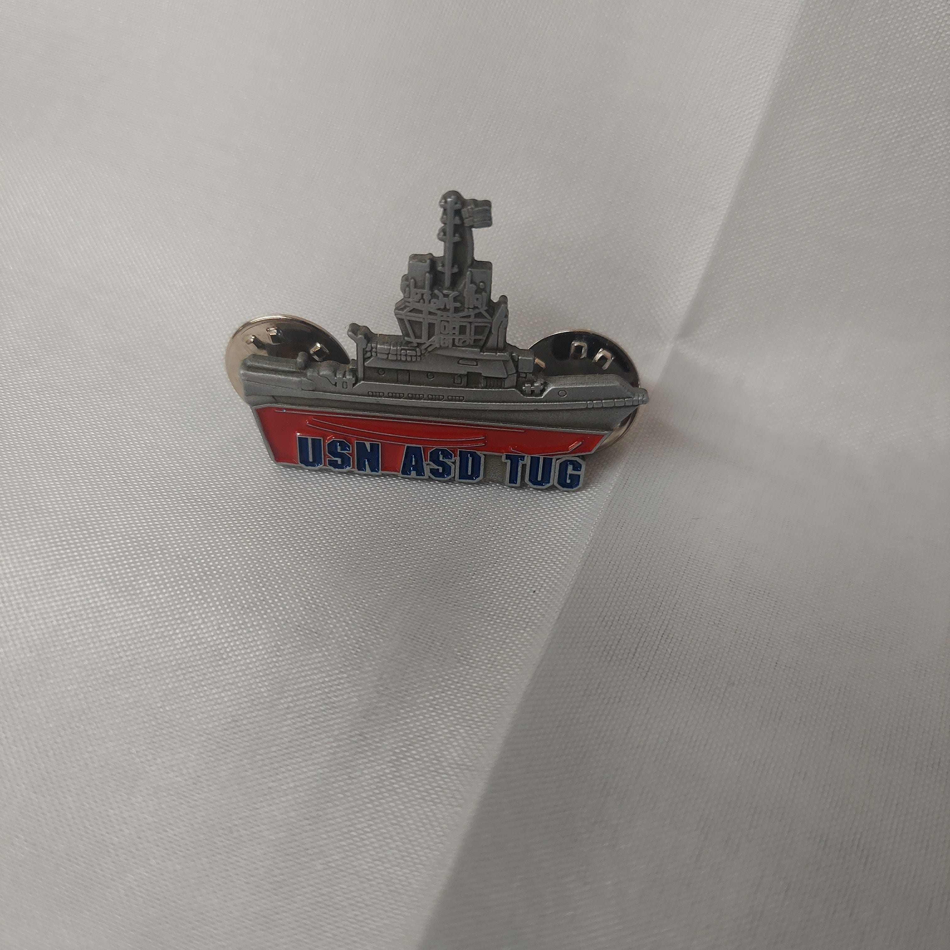 Large ASD Tug PinLarge ASD Tug Navy metal pin. The metal pin is grey w ...